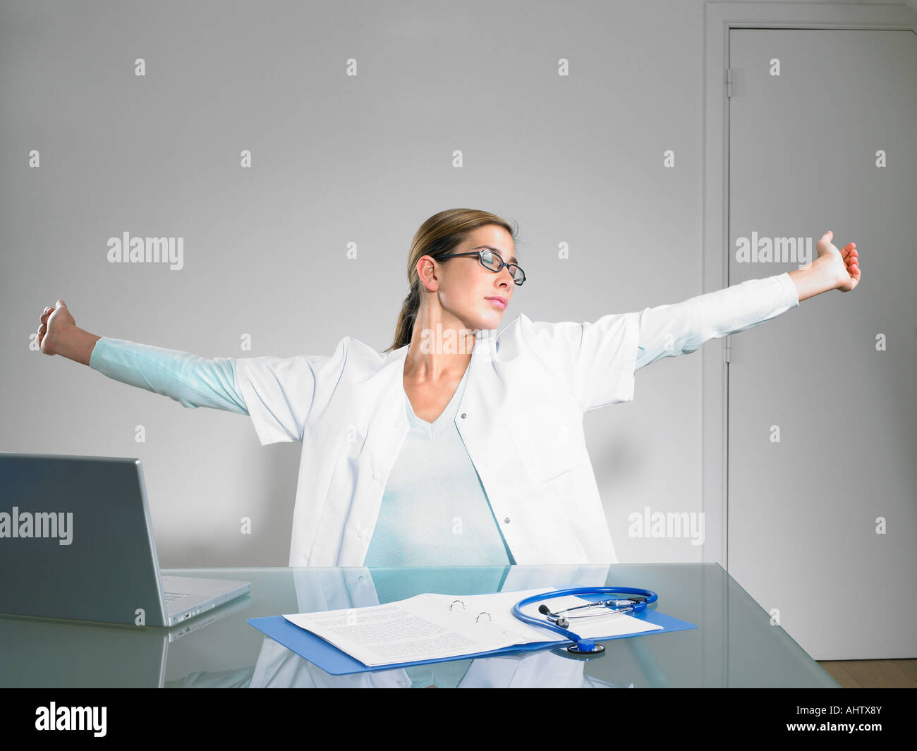 Stretching female doctor at her desk Stock Photo - Alamy