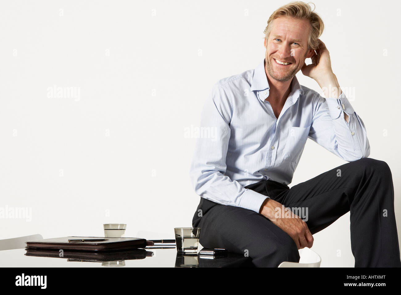 Young businessman seated on desk Stock Photo - Alamy