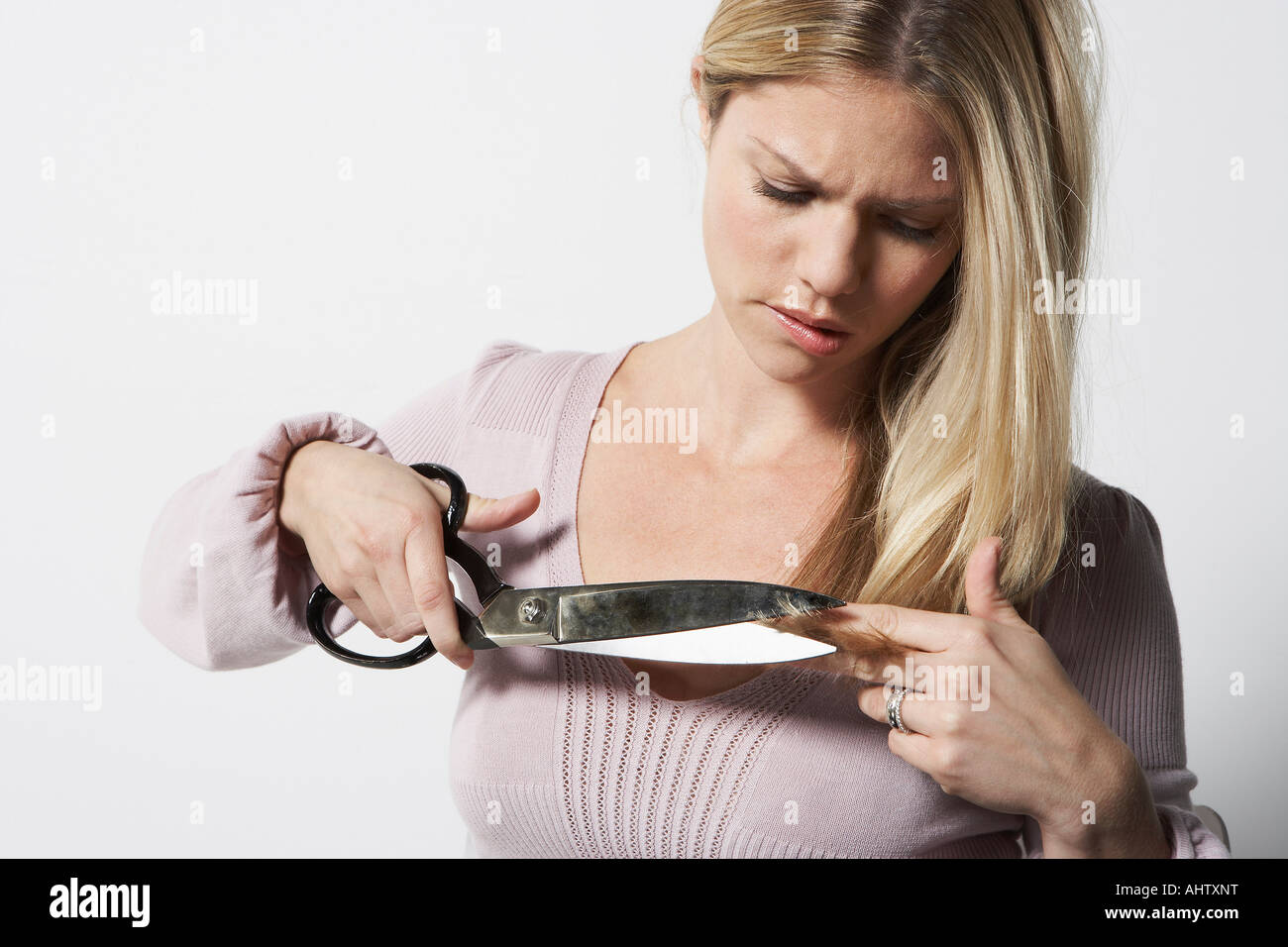 Young woman cutting her own hair with a large pair of scissors Stock ...