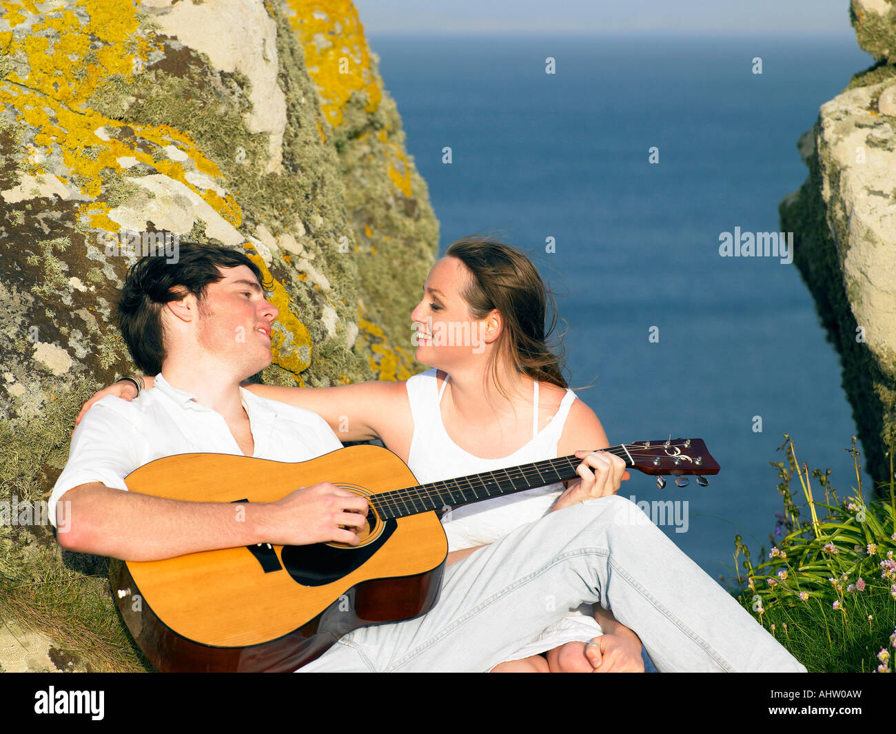 Young couple on a cliff playing guitar Stock Photo - Alamy