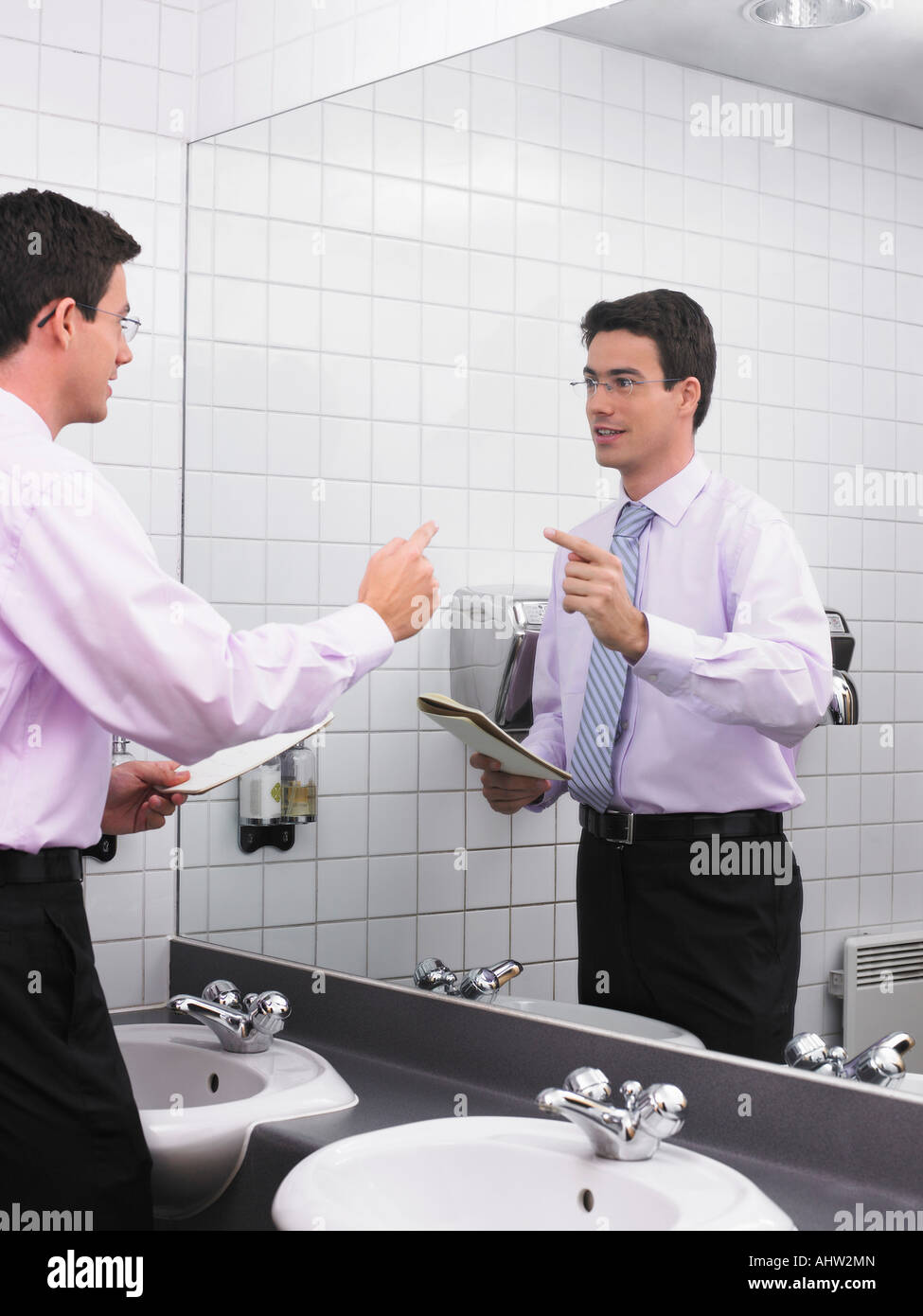 Man practicing speech in office washroom mirror Stock Photo - Alamy