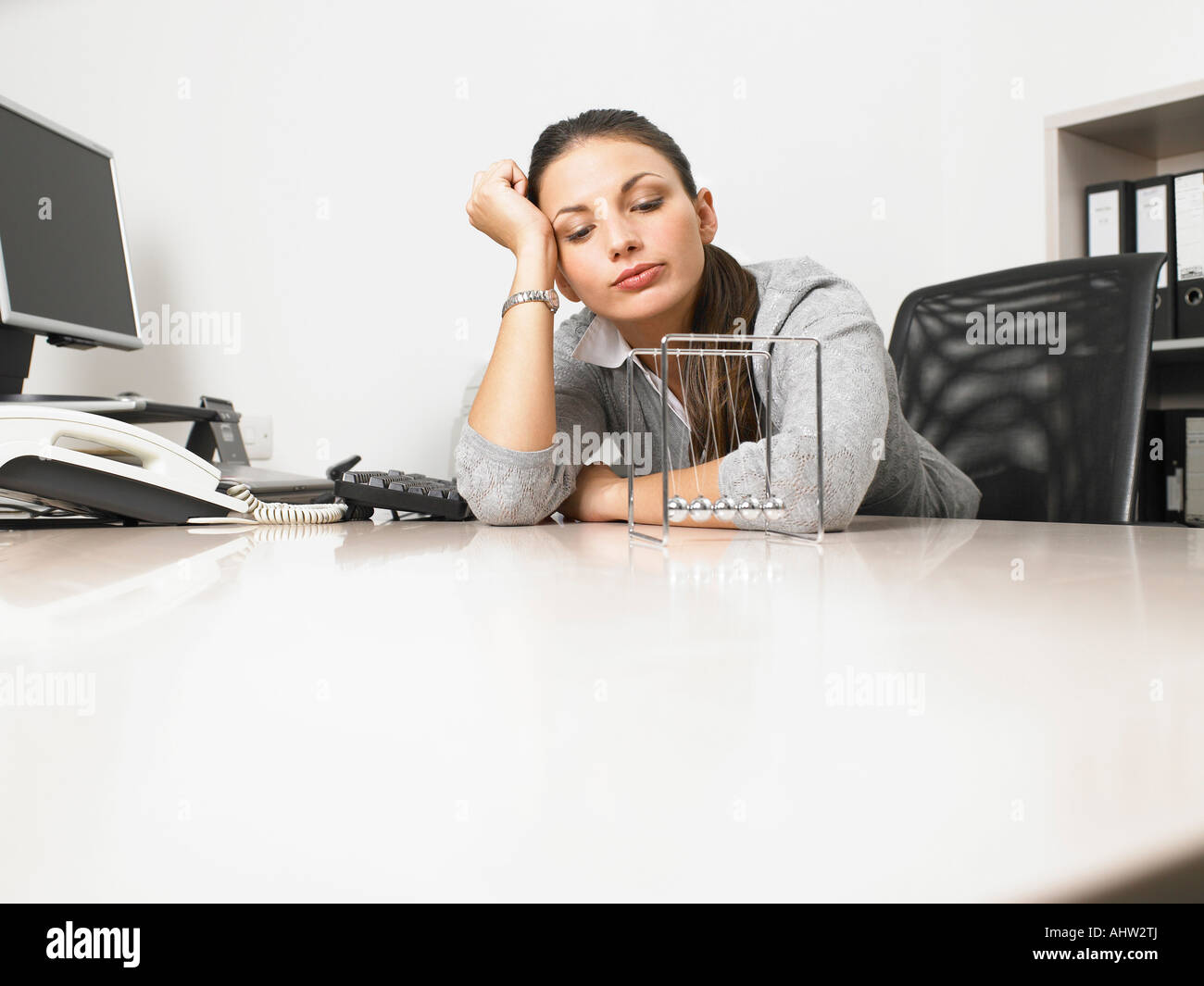 Businesswomen sitting at her desk with a Newton's Cradle Stock Photo ...