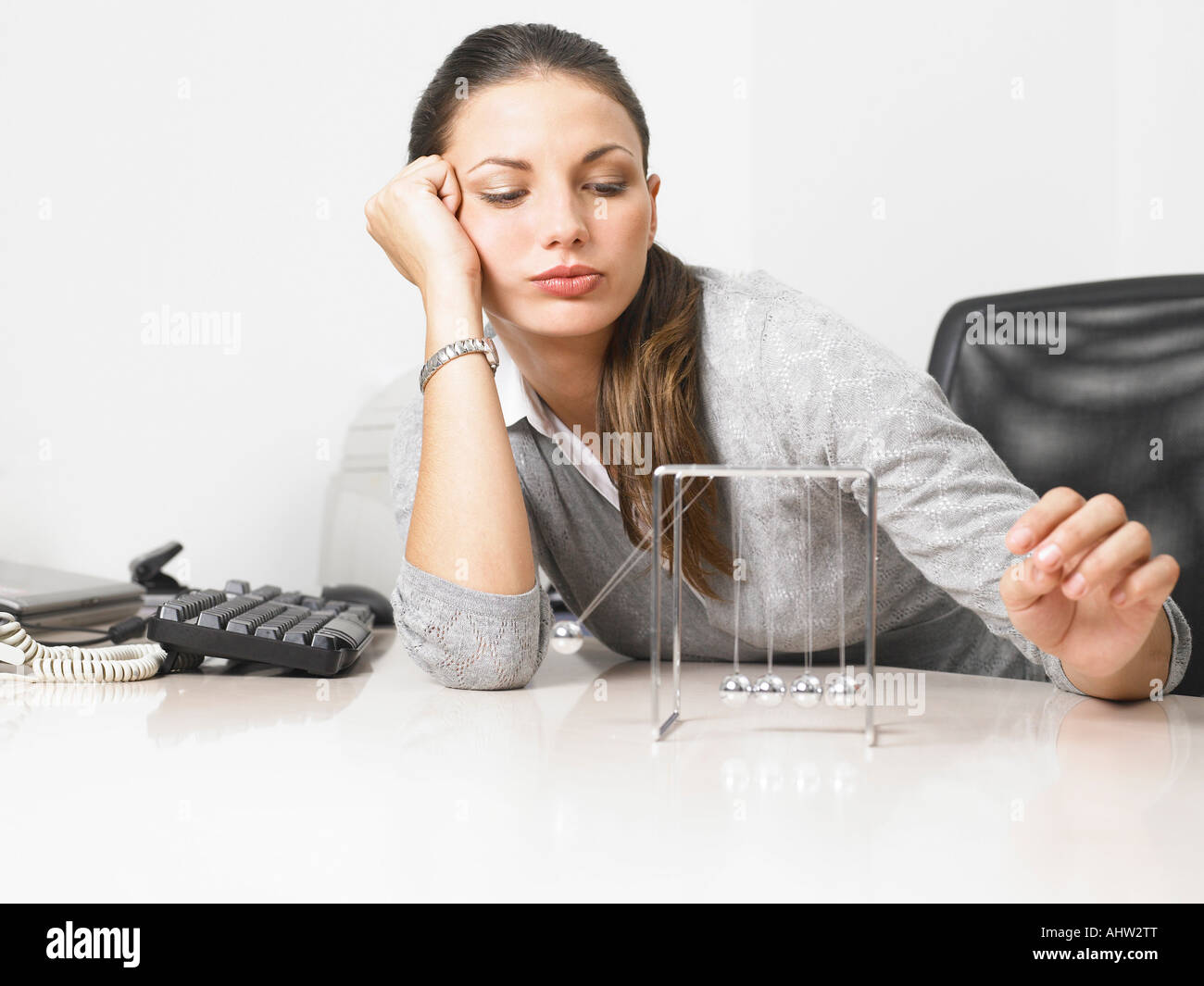 Businesswomen sitting at her desk with a Newton's Cradle Stock Photo ...