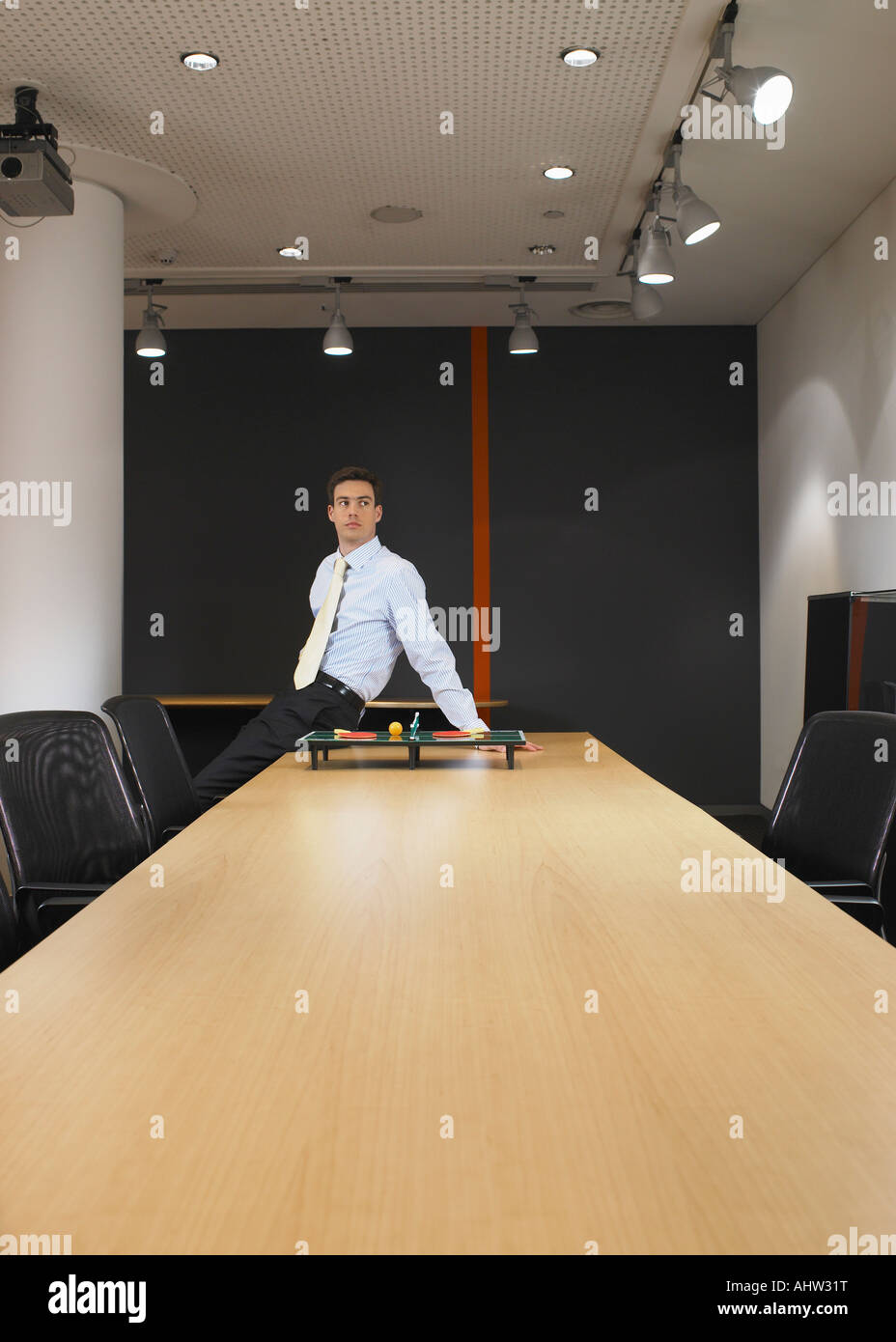 Portrait of young man sitting at boardroom table with miniature table ...