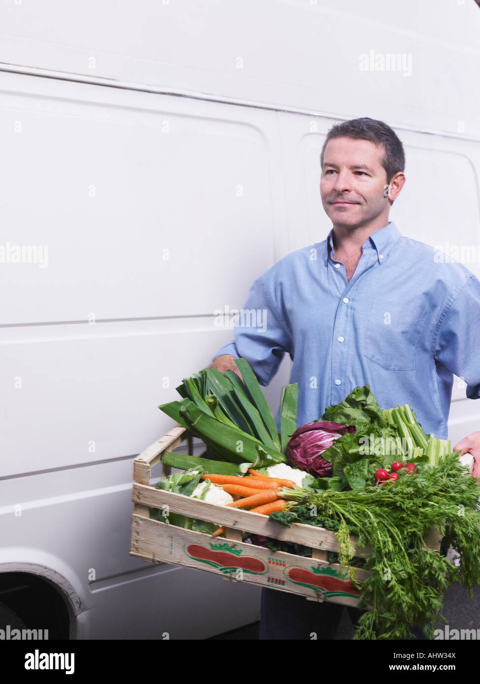 Man carrying crate of vegetables from van Stock Photo - Alamy