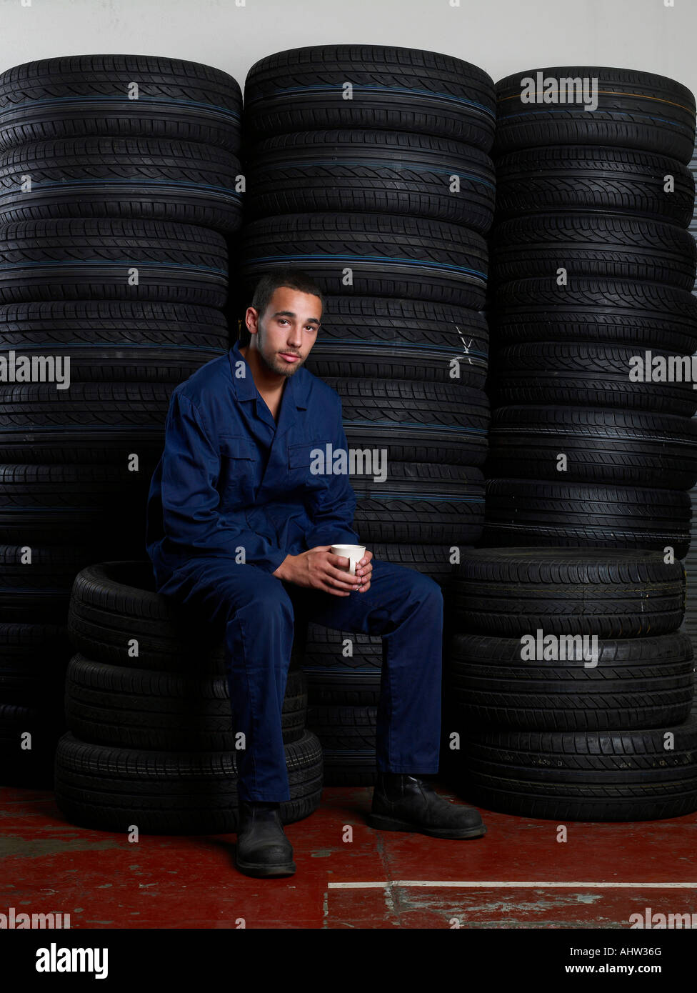 Mechanic sitting on a stack of tires Stock Photo - Alamy