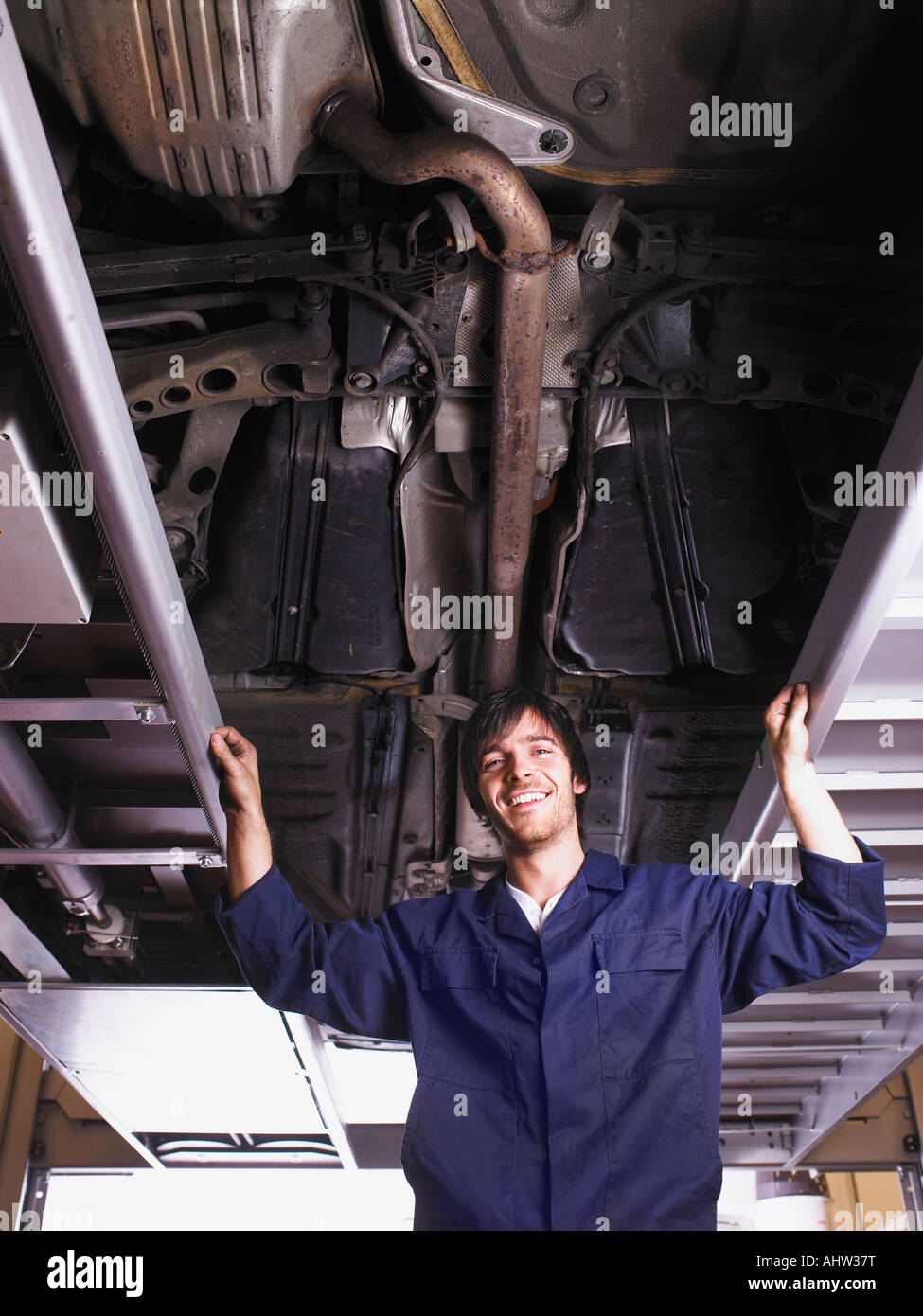 Mechanic standing under raised car Stock Photo - Alamy