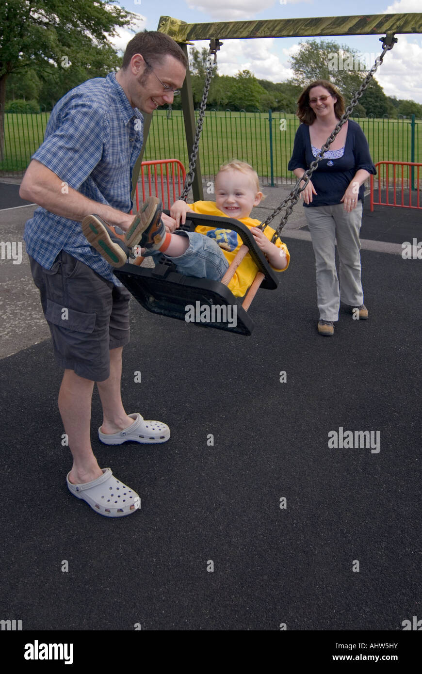 Vertical close up of a baby boy having great fun being pushed on a ...