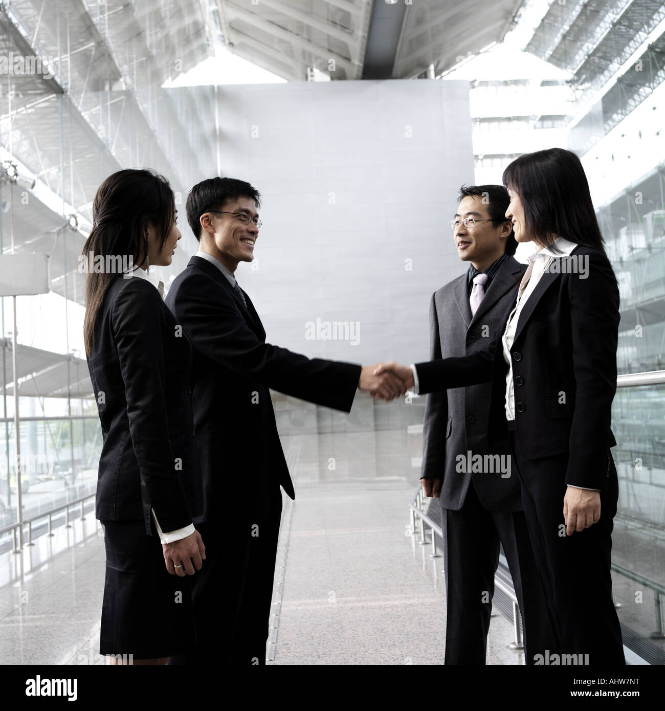 A group of business professionals shake hands in a modern building ...