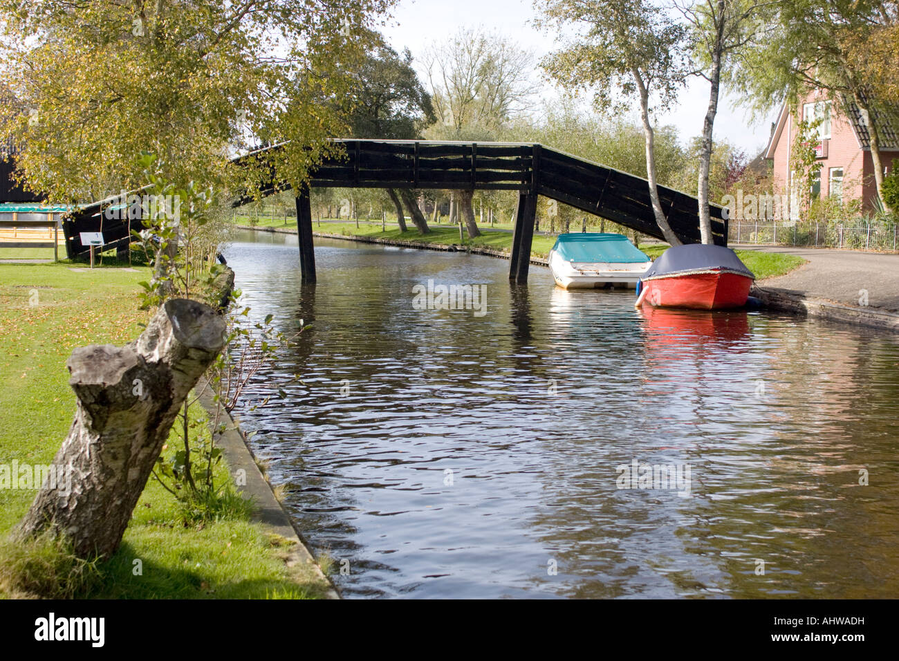 Channel with traditional wooden footbridge and boats Stock Photo - Alamy