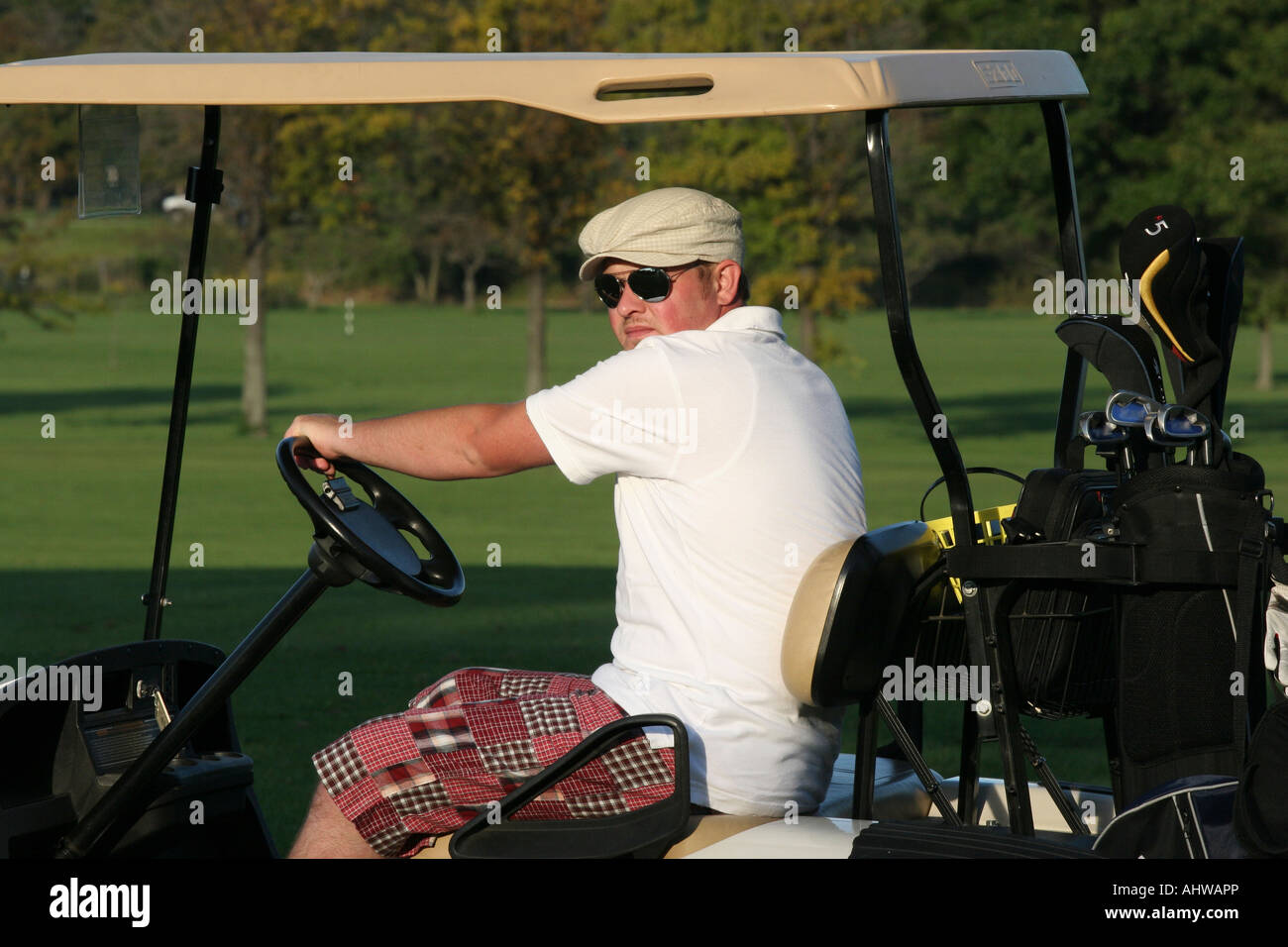 American golfer man with golf clubs in bag sitting in a golf cart on ...