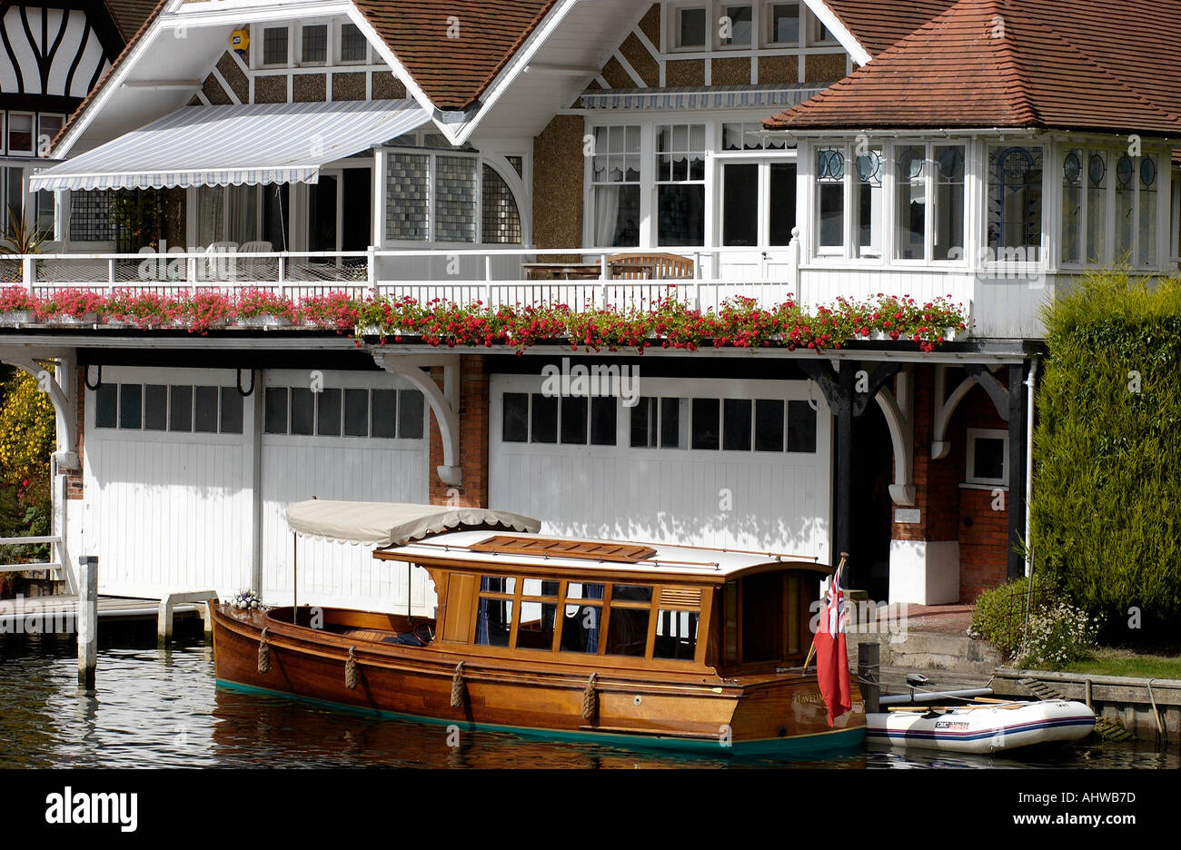 A traditional motor launch by a boathouse on the River Thames at Henley ...