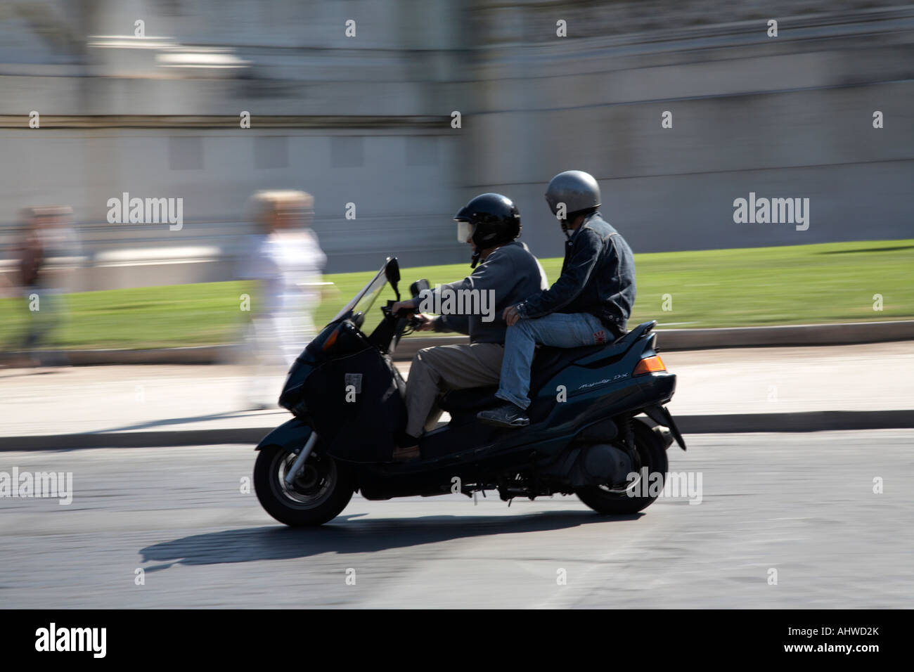 Scooter with driver and pillion passenger speeds through Piazza Venezia ...