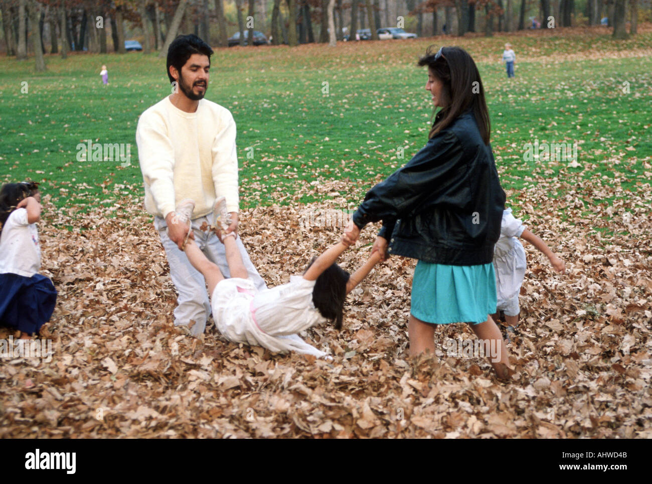 Arab American family play in the park with their children in the leaves ...