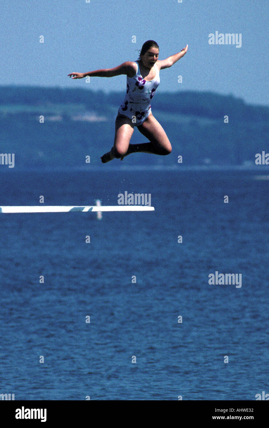 Teen female leaps from a diving board into the water Stock Photo - Alamy