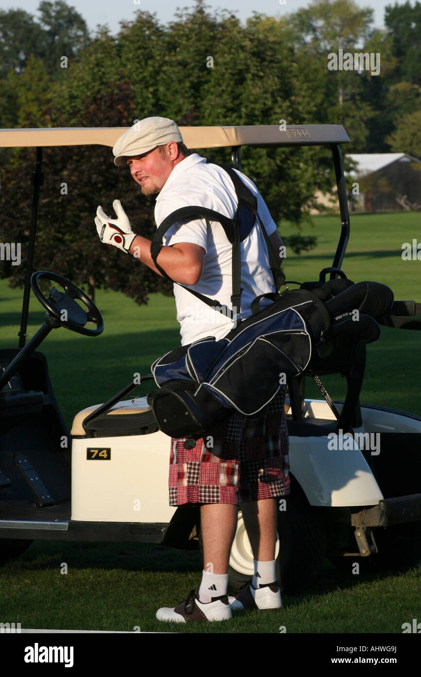 American golfer man with golf clubs in bag and a golf cart on the golf ...