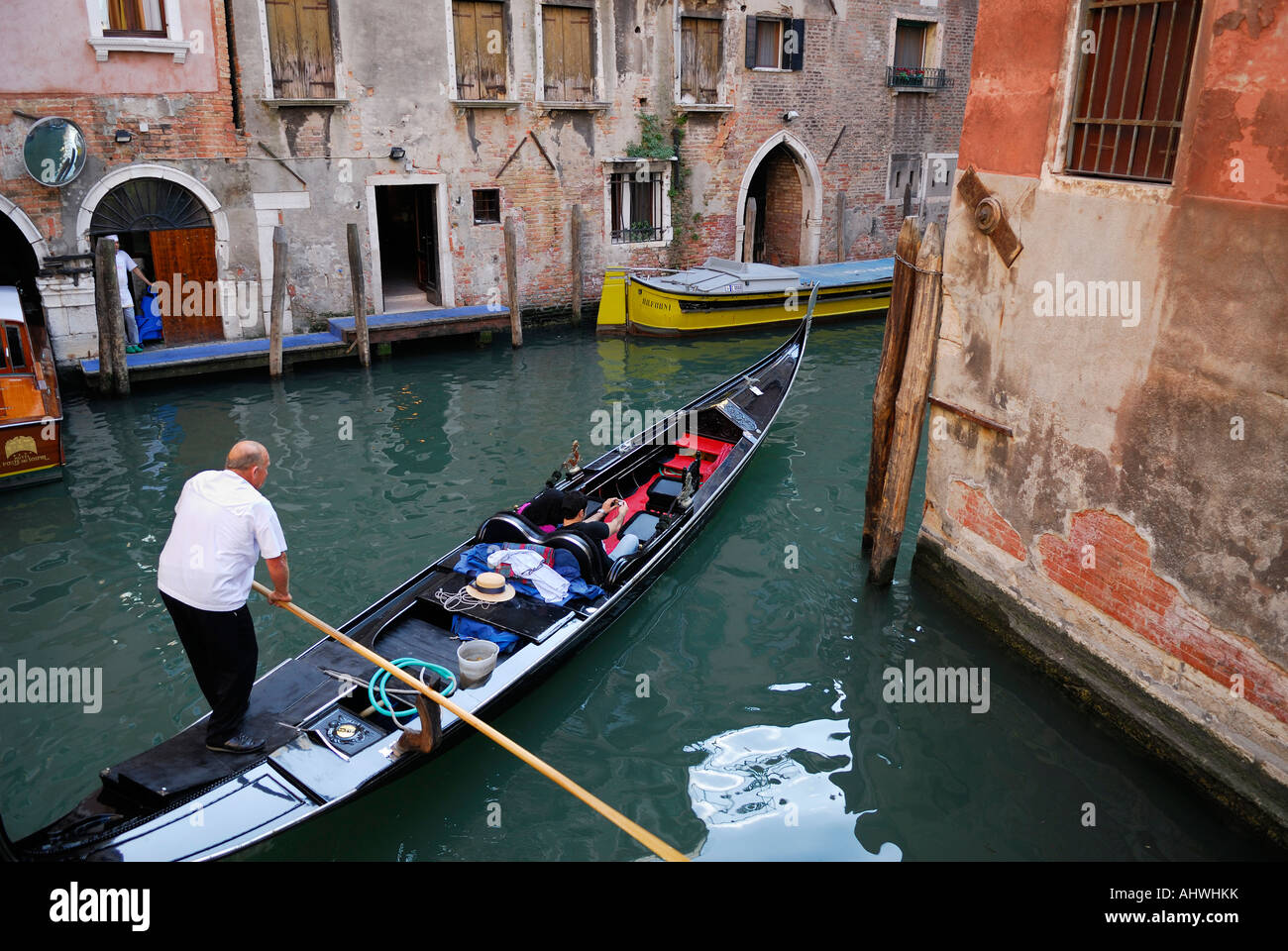 Gondolier maneuvering his gondola boat around a canal corner in Venice ...