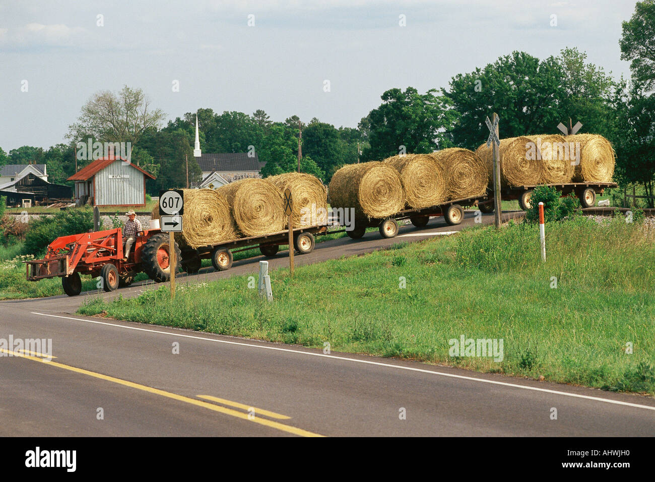 Tractor pulling flatbeds with rolled hay bales Stock Photo - Alamy