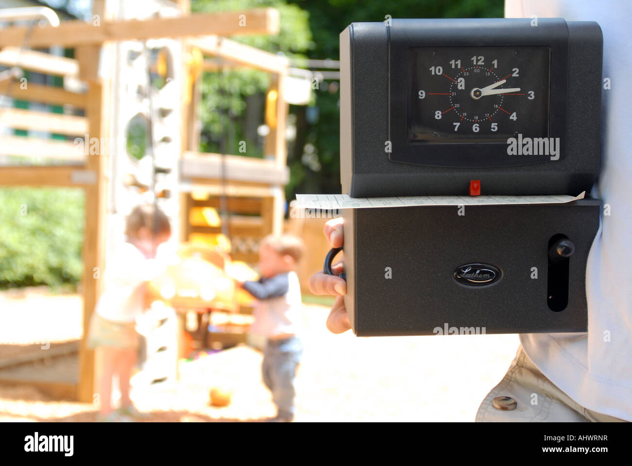 Electronic time clock held by mother in front of playground Stock Photo ...