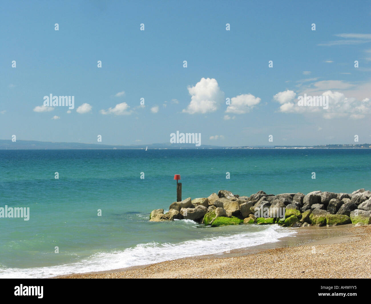 Coastal scene with pebbled beach, rolling waves and blue skies with ...