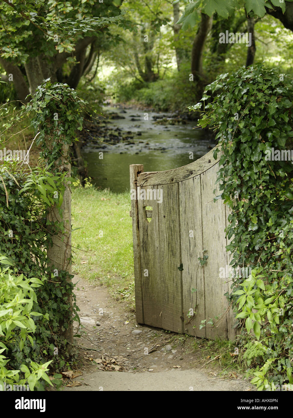 Pretty open Gate leading into a country garden with a river running ...
