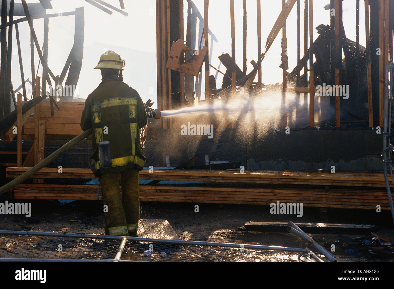 Firefighter hosing down building Stock Photo - Alamy