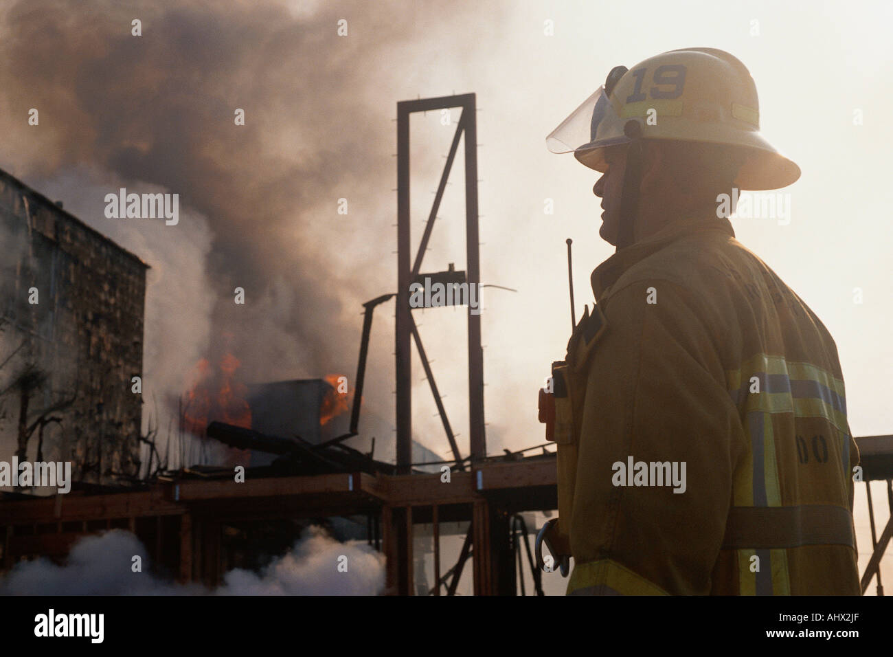 Firefighter with smoldering building in background Stock Photo - Alamy