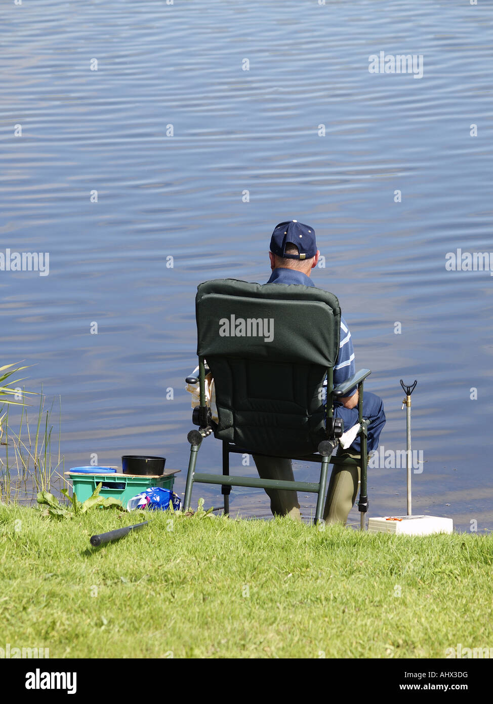 Man sitting on a fishing chair beside a river bank, fishing Stock Photo ...