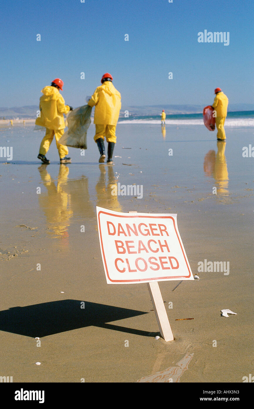 Clean up crew on beach and warning signage Stock Photo - Alamy