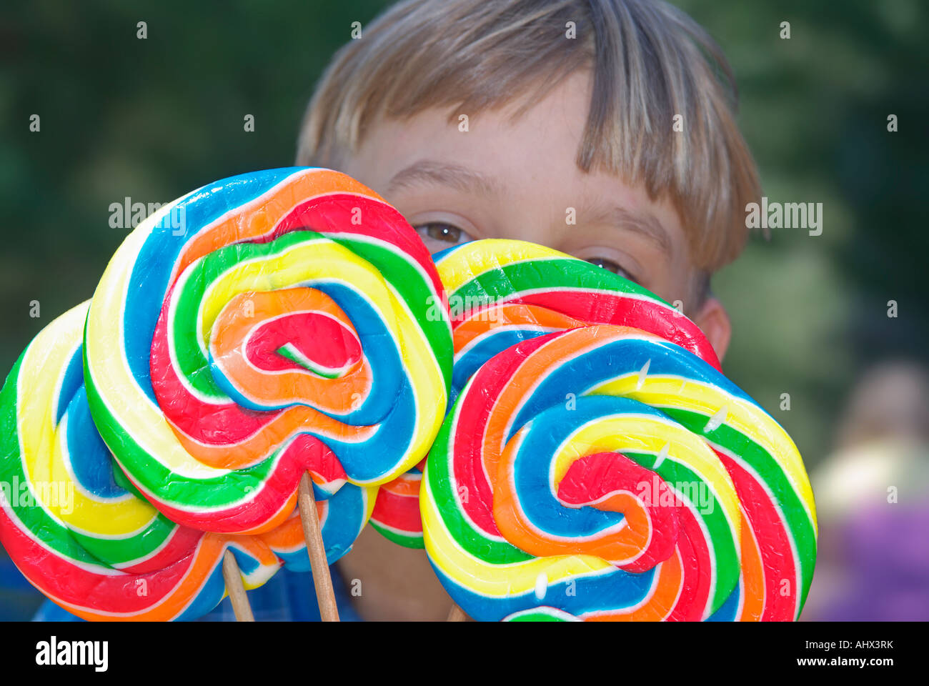 young boy looks over the top of four huge lollipops Stock Photo - Alamy