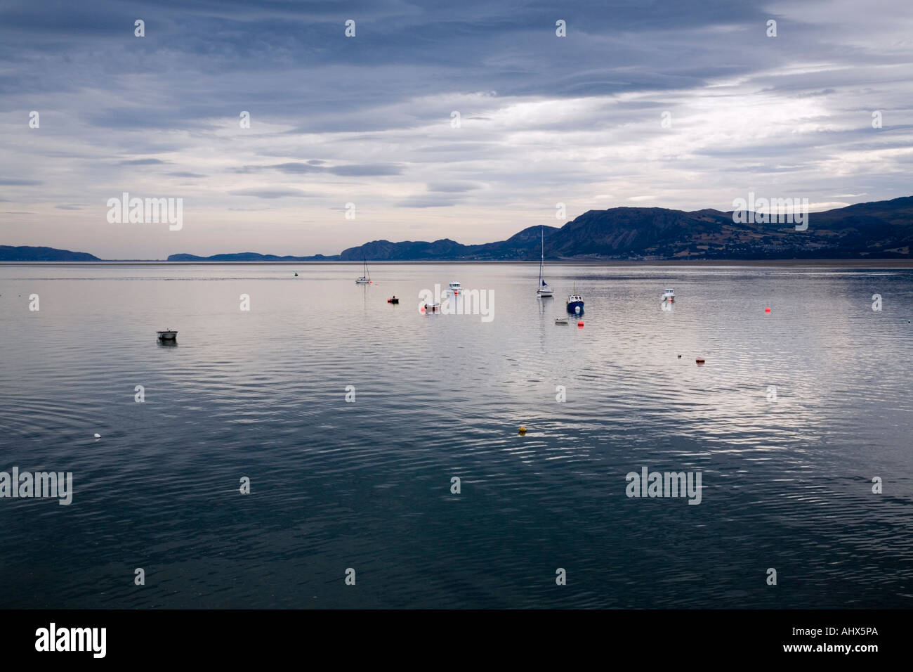 Boats on calm water of Menai Strait on North Wales coast with grey ...