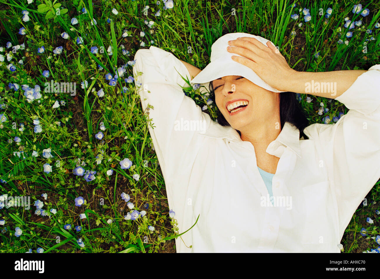 Happy woman lying in field of flowers Stock Photo - Alamy