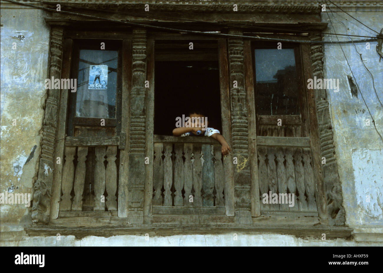 Girl looking from wooden window in Newari style Kathmandu Valley Nepal ...