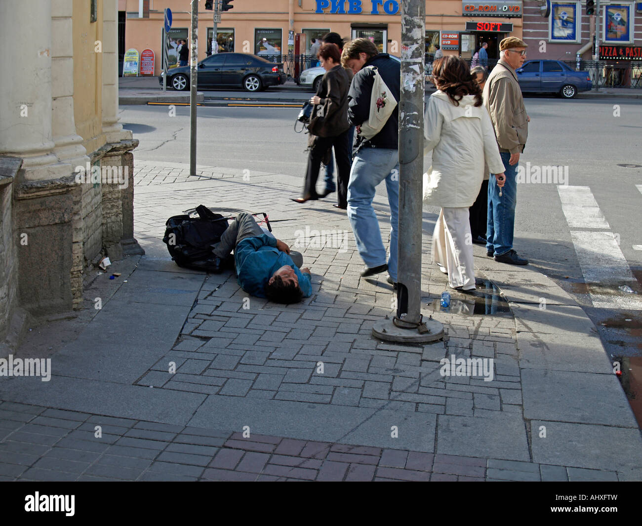 homeless person beggar lying on on pavement while passanges getting by ...
