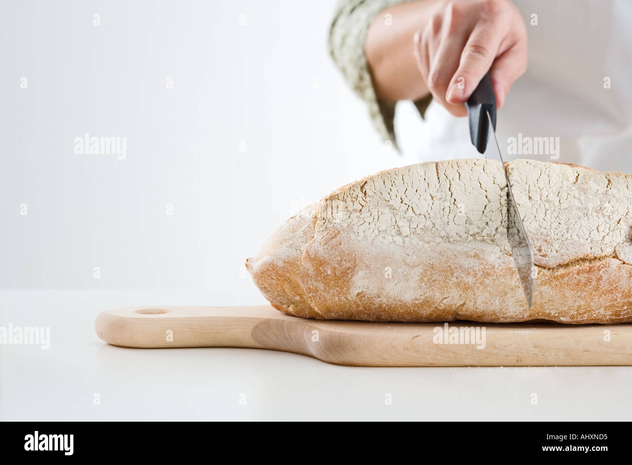 Hand cutting loaf of bread Stock Photo - Alamy