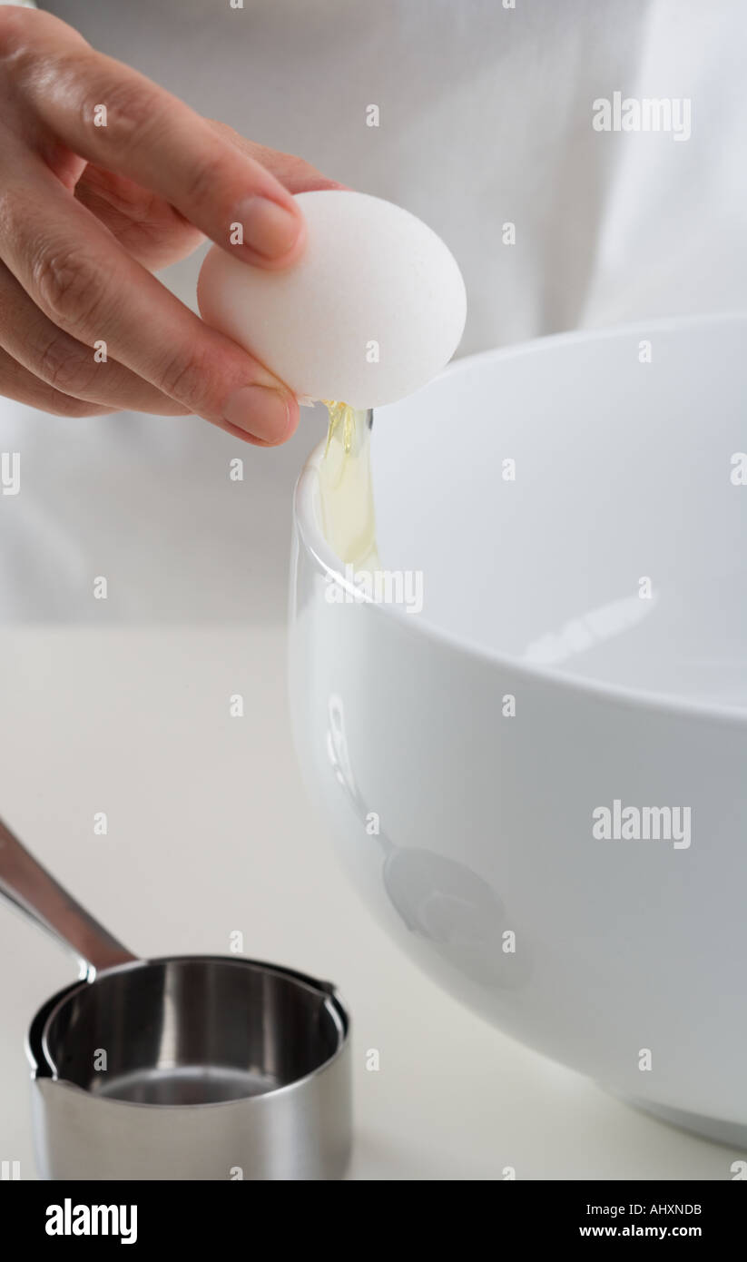 Hand cracking egg into bowl Stock Photo - Alamy