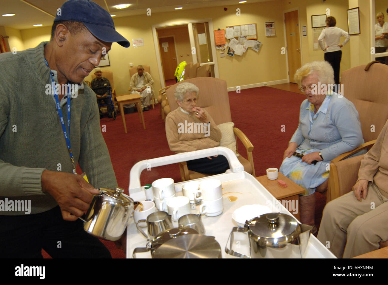 A Care Assistant serves tea to elderly people in a multi cultural day ...