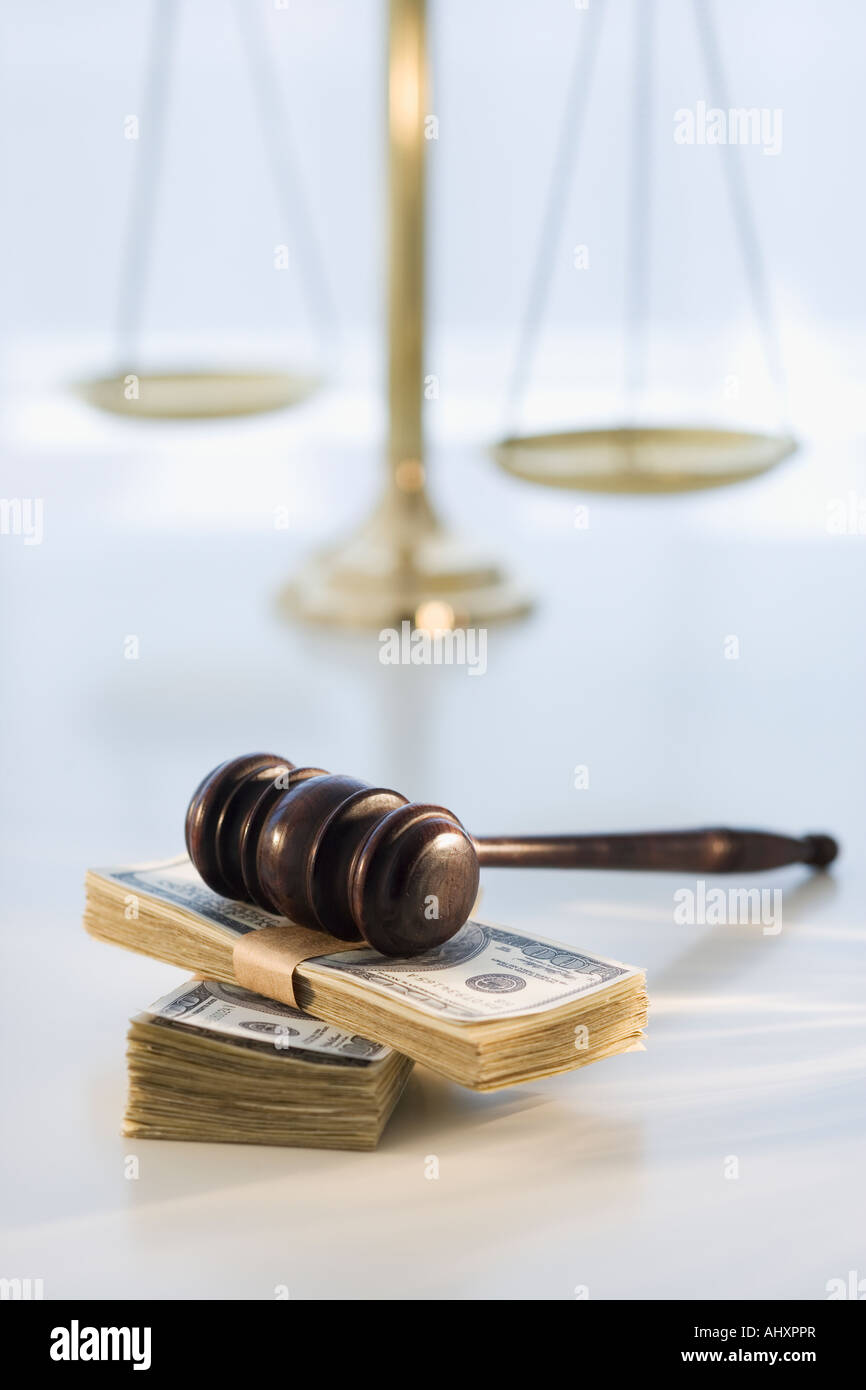 Gavel on stack of money with scales in background Stock Photo - Alamy