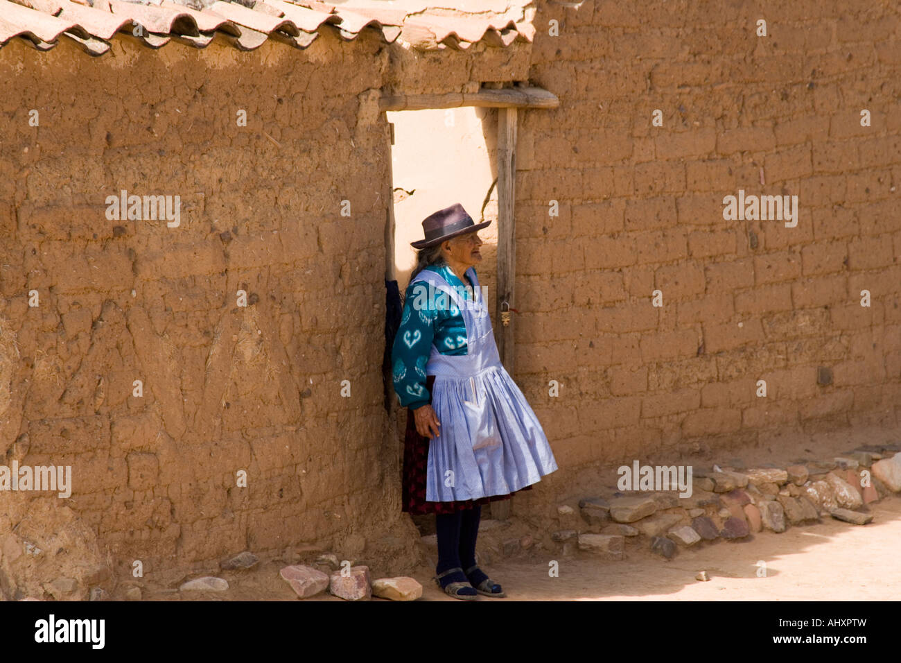 Old Indian Aymara woman and an adobe house on the road between Tarabuco ...