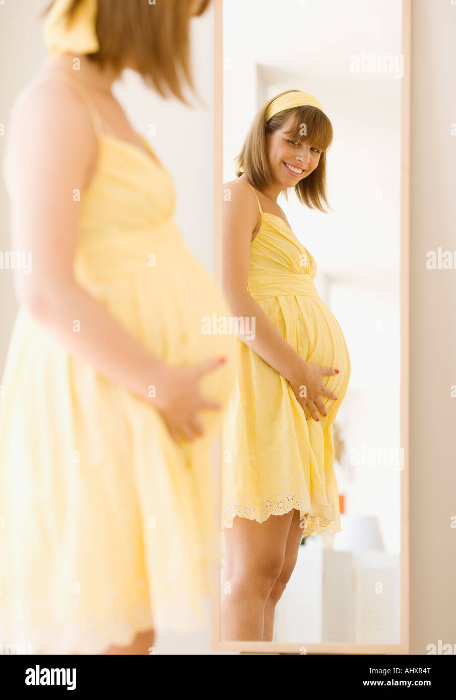 Pregnant woman looking in mirror Stock Photo - Alamy
