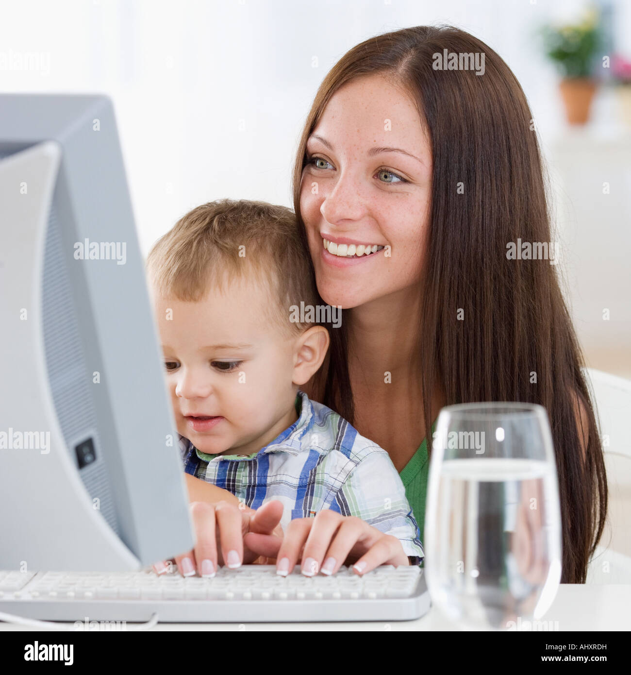 Mother holding baby and typing on computer Stock Photo - Alamy