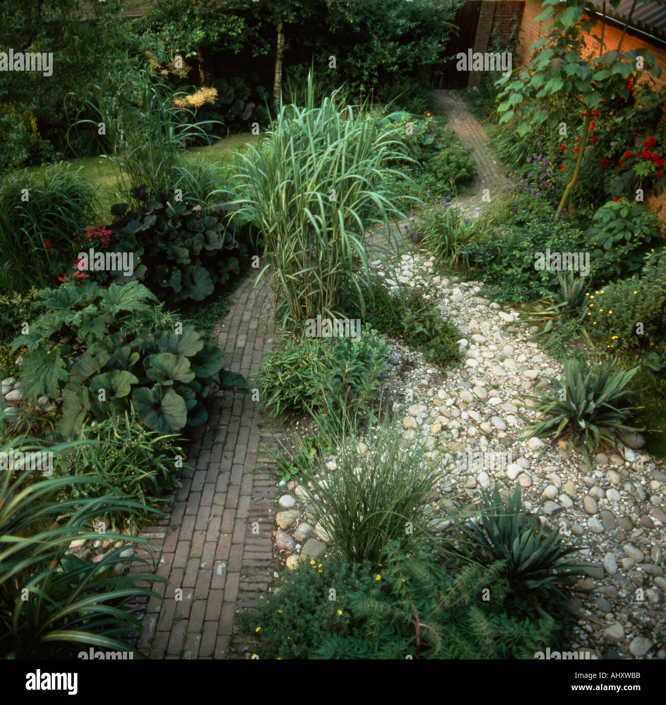 Birdseye view of paved path divided by green shrubs from curved pebbled ...