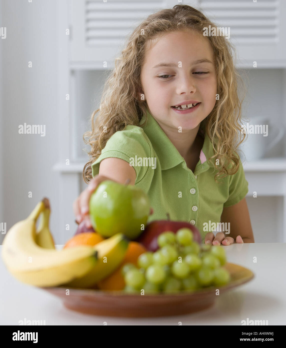 Girl reaching for fruit in bowl Stock Photo - Alamy