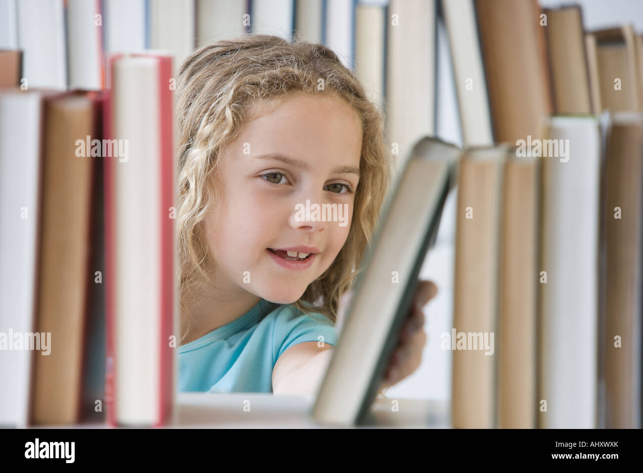 Girl looking at books on shelf Stock Photo - Alamy