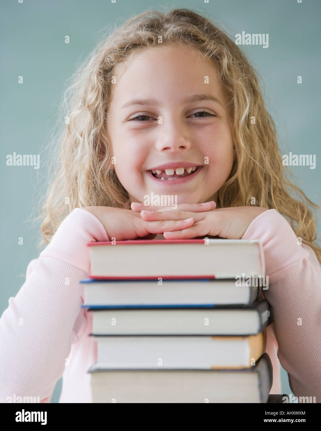 Girl leaning on stack of books Stock Photo - Alamy