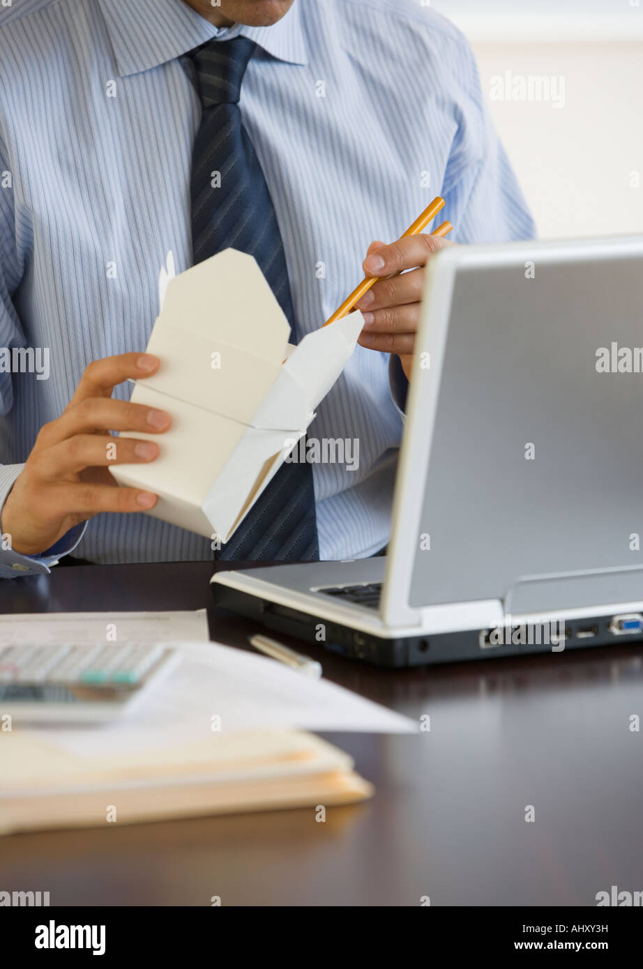 Businessman eating take out at desk Stock Photo - Alamy