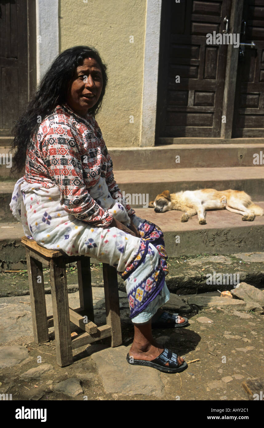 Mid aged Nepali woman with long hairs sitting on chair with slipping ...