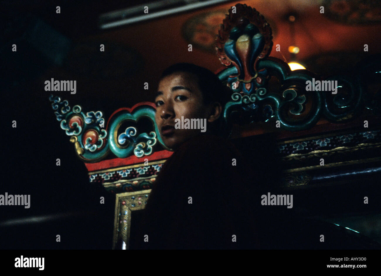 A mysterious Tibetan monk looks over his shoulder inside a dimly lit ...