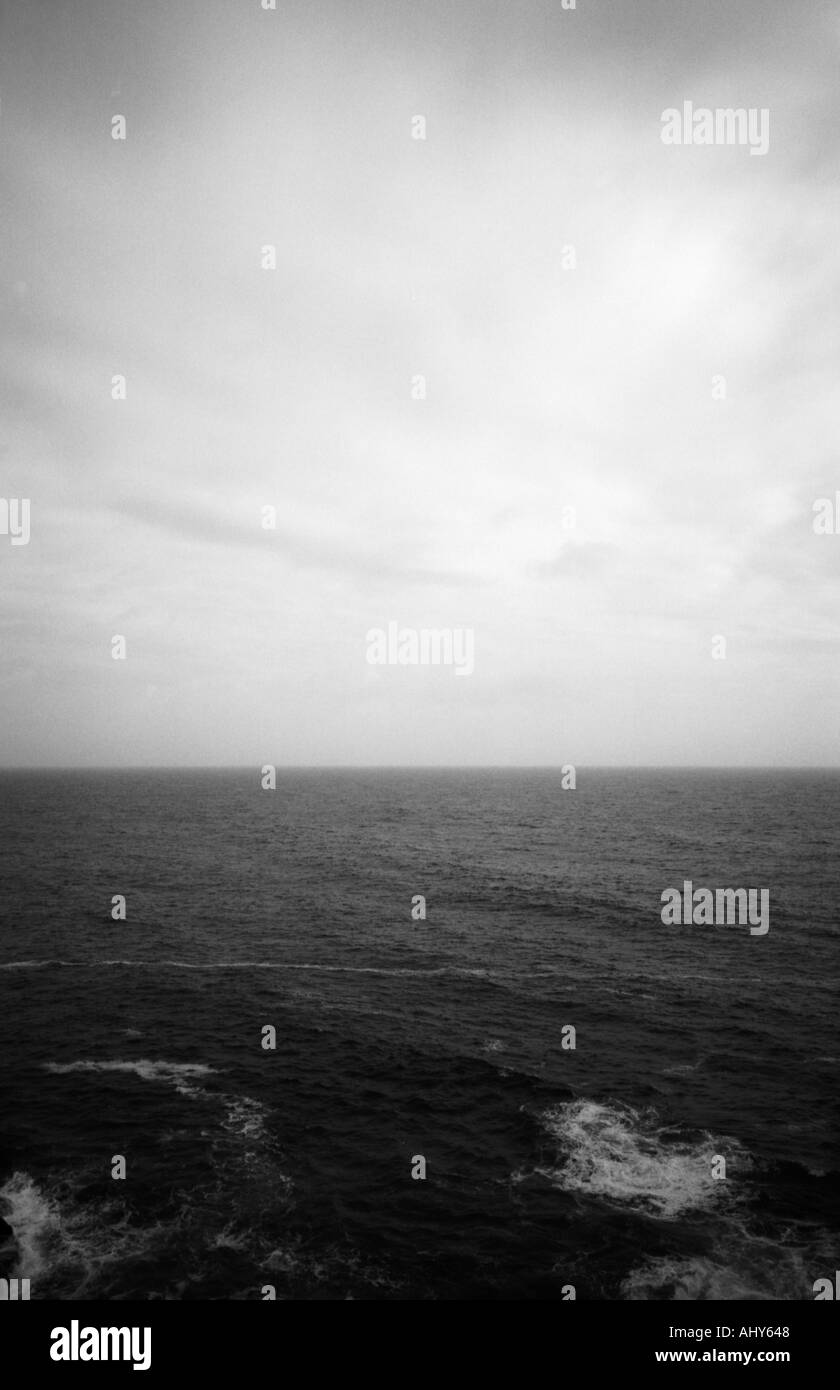 black and white image looking out towards a calm sea taken in cornwall ...