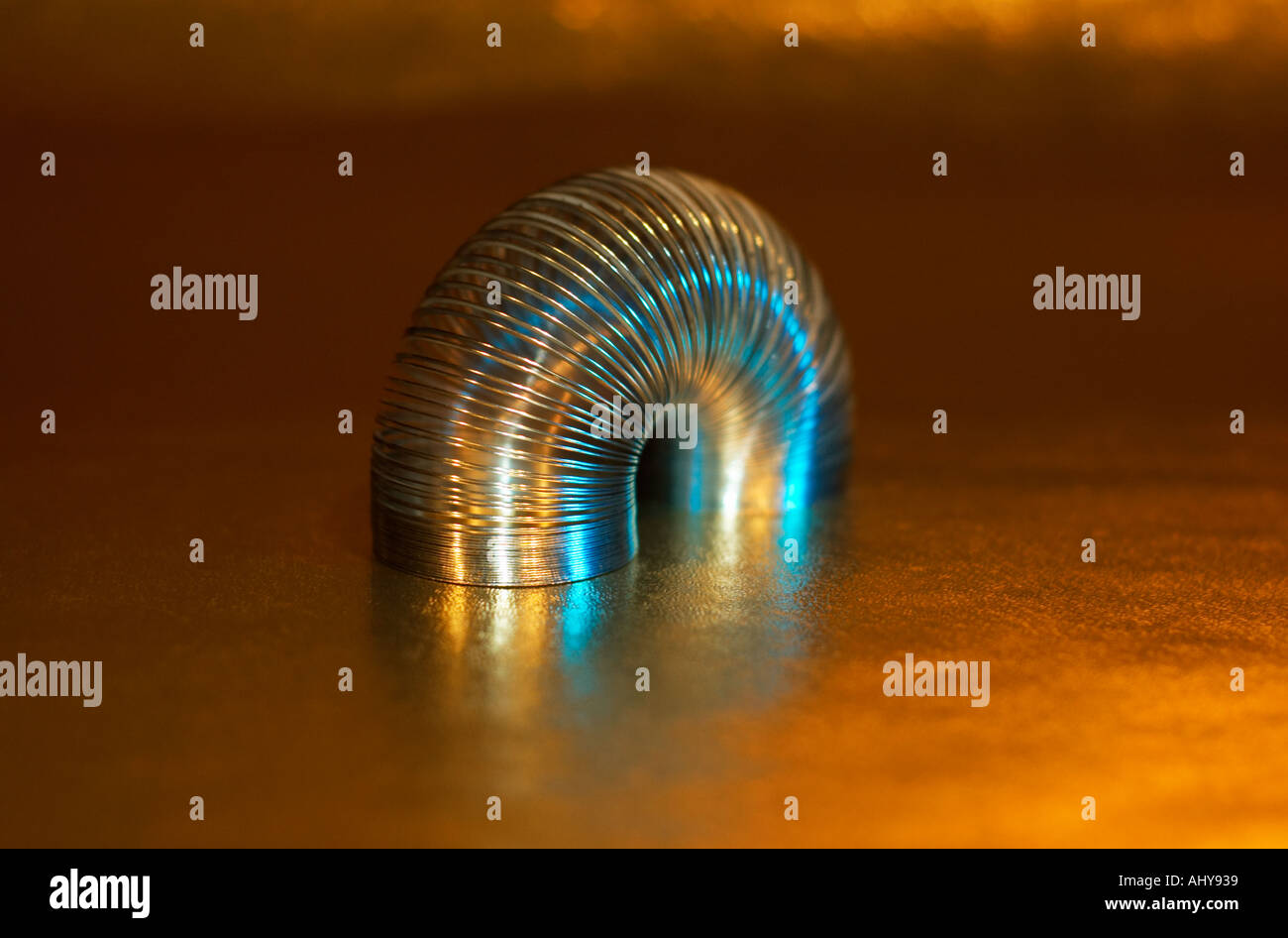 Slinky spring coiled with golden and blue lighting Stock Photo - Alamy